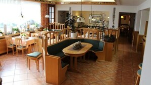 Uma ampla sala de jantar com móveis de madeira e uma grande janela que oferece iluminação natural.