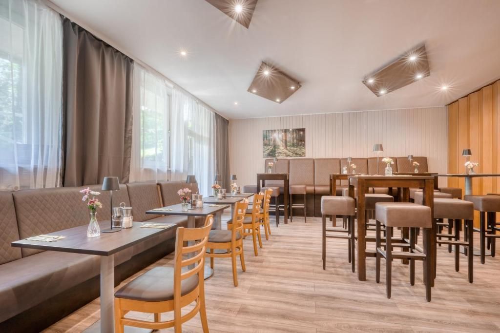 Uma sala de jantar de hotel com uma mesa comprida, várias cadeiras e um sofá.