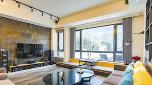 Uma sala de estar moderna com lareira de pedra, televisão de tela plana, mesa de centro e sofá com almofadas coloridas.