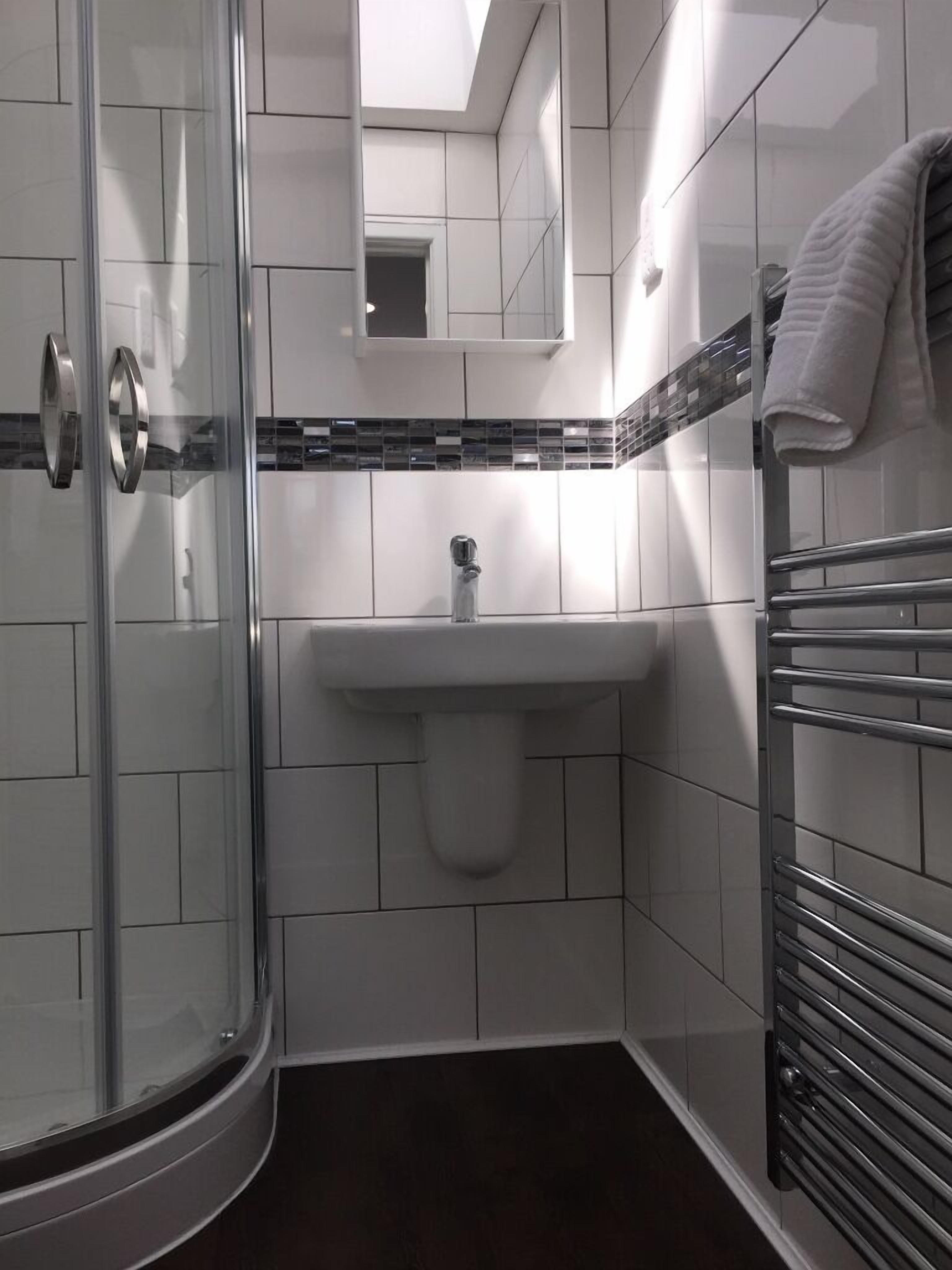 Uma casa de banho moderna com cabine de duche em vidro, uma sanita branca e um porta-toalhas.