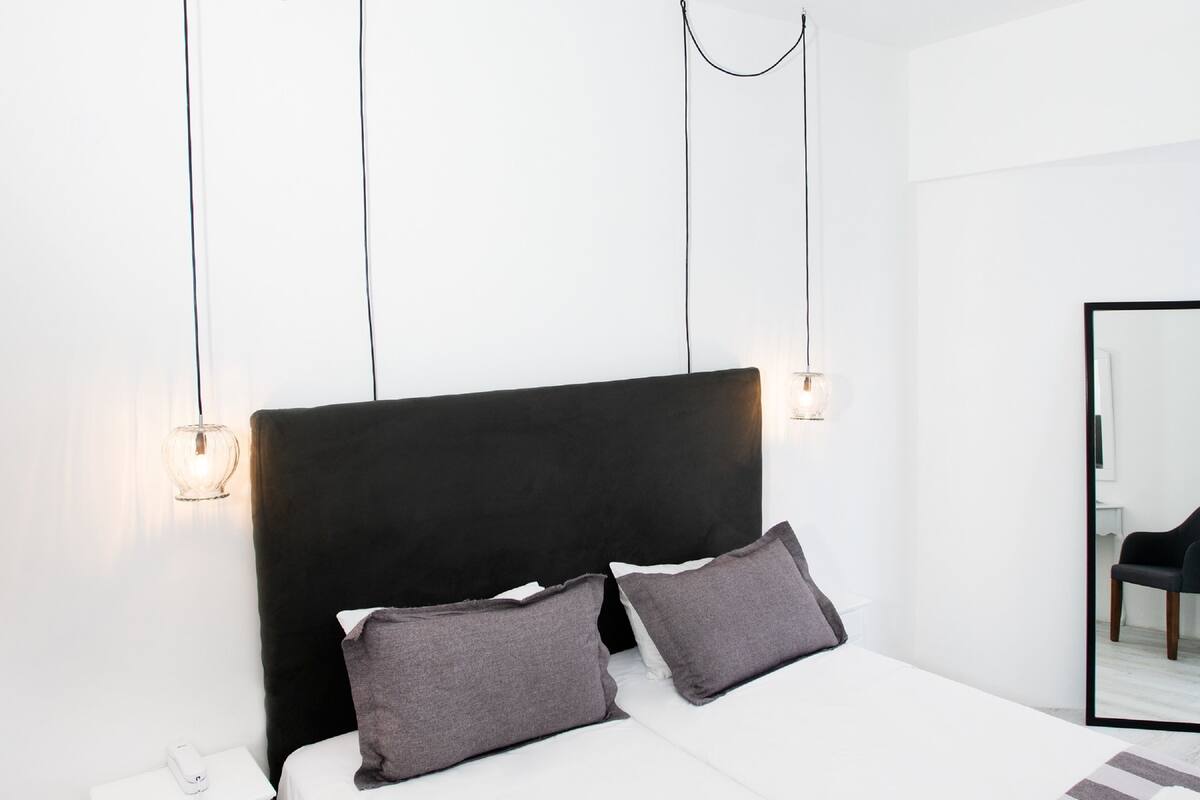 Um quarto moderno com uma cama grande, mesas de cabeceira e iluminação embutida na parede.