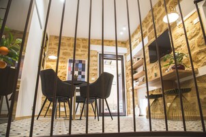 Uma sala de jantar com uma mesa e cadeiras, uma televisão na parede e uma planta.