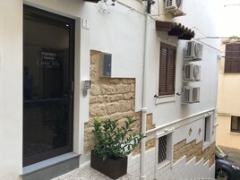 Um edifício com fachada de pedra, porta com painel de vidro e vários aparelhos de ar condicionado.