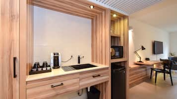 Cozinha moderna com armários de madeira, pia embutida, máquina de café e micro-ondas.