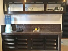 Uma cozinha com dispensador de água, pia e bancada.