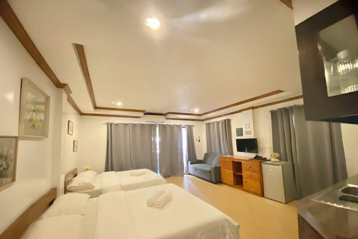 Quarto de hotel com duas camas, uma mesa de escritório, televisão e minibar.