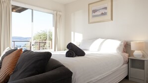 Quarto de hotel com cama, sofá, mesa de cabeceira e janela com vista.