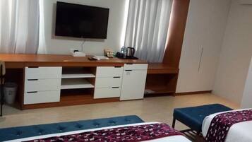 Quarto de hotel com cama, escrivaninha e televisão de tela plana, e um guarda-roupa.
