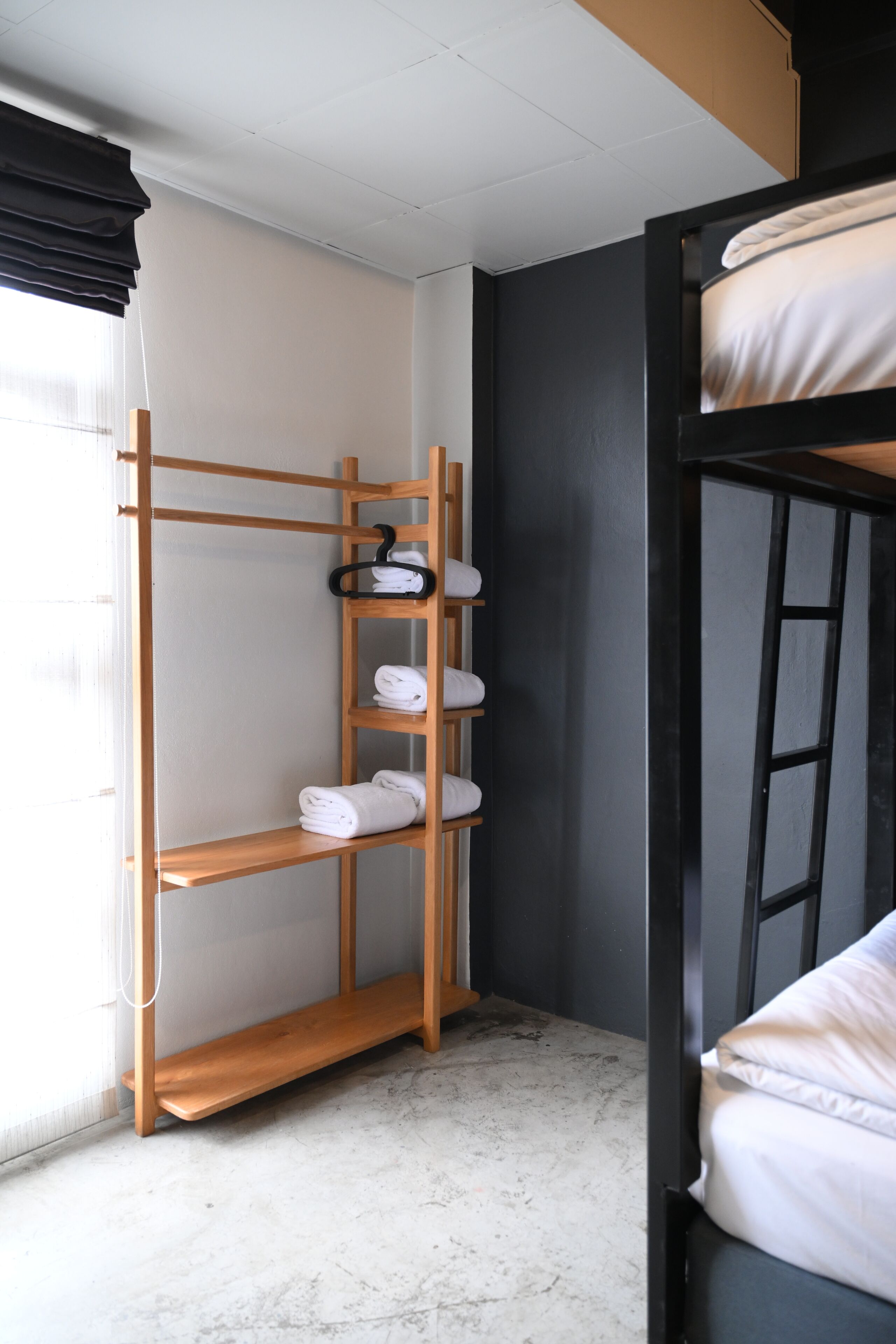 Uma cama beliche com uma estante de madeira encostada à parede, com toalhas dobradas.