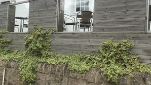 O Riccarton Inn, um pub e restaurante com fachada branca e uma parede de pedra à frente.