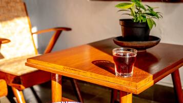 Uma mesa de madeira com um copo de líquido vermelho, uma planta em vaso e uma cadeira.