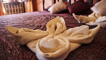 Uma cama com colcha estampada, cabeceira de madeira e almofada decorativa.