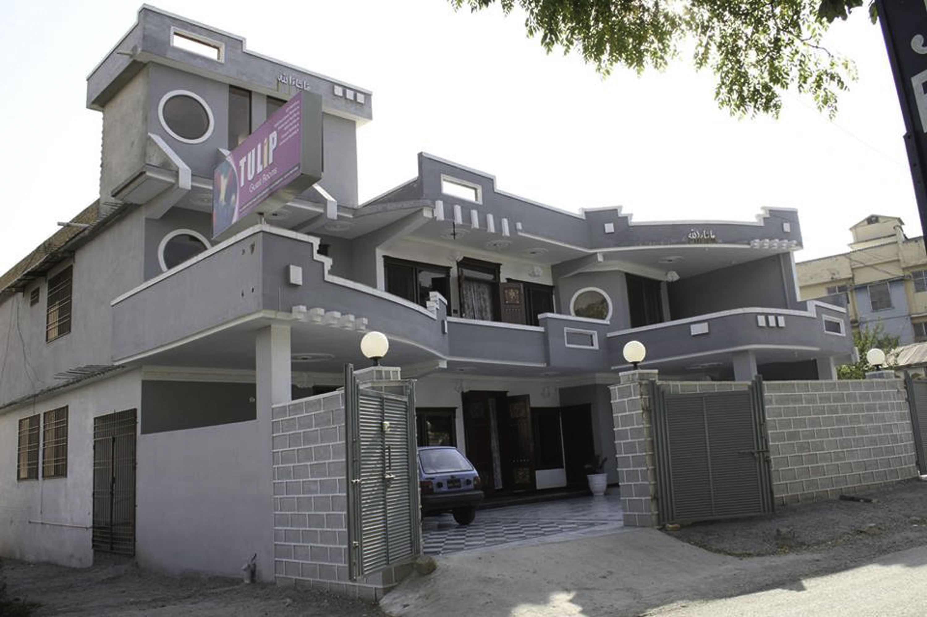Uma casa moderna de dois andares, com varanda, garagem e portão fechado.