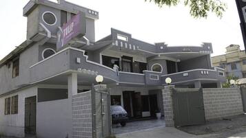 Uma casa moderna de dois andares, com varanda, garagem e portão fechado.