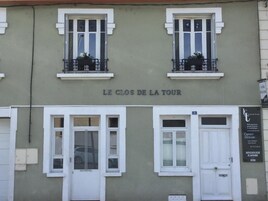 Fachada de edifício com a placa “LE CLOS DE LA TOUR”, indicando um hotel ou estabelecimento similar.