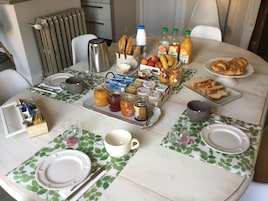 Uma mesa de café da manhã posta com diversos alimentos, incluindo pão, frutas e bebidas.