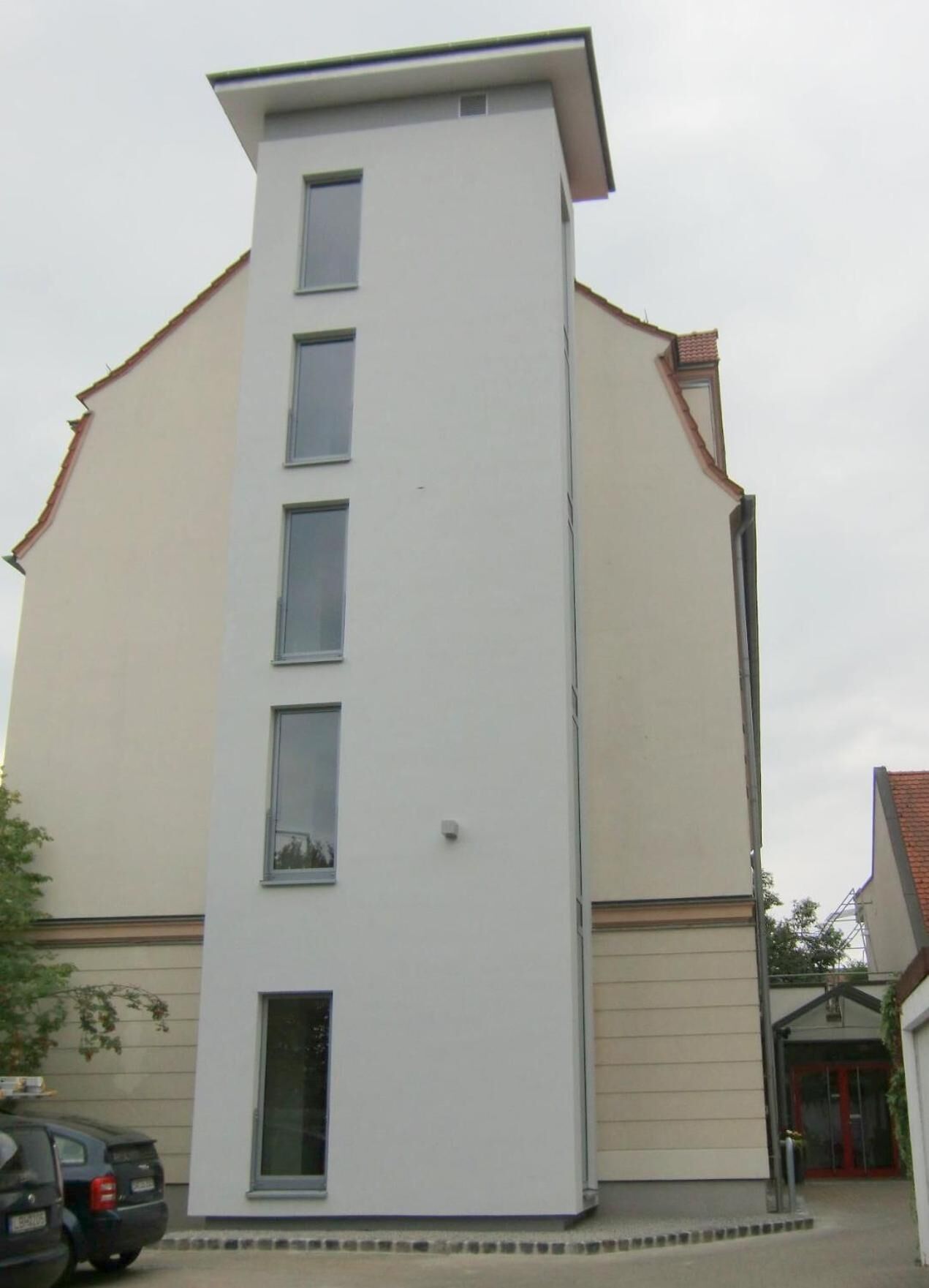 Um edifício moderno de dois andares com telhado plano e uma seção vertical central com janelas.