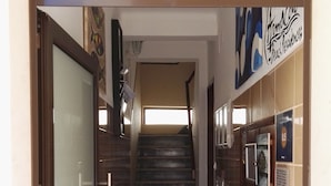 Um corredor com piso de mármore, uma escada e uma placa indicando a sala 8.5.