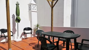 Pátio externo com pergolado de madeira, mesa e cadeiras.