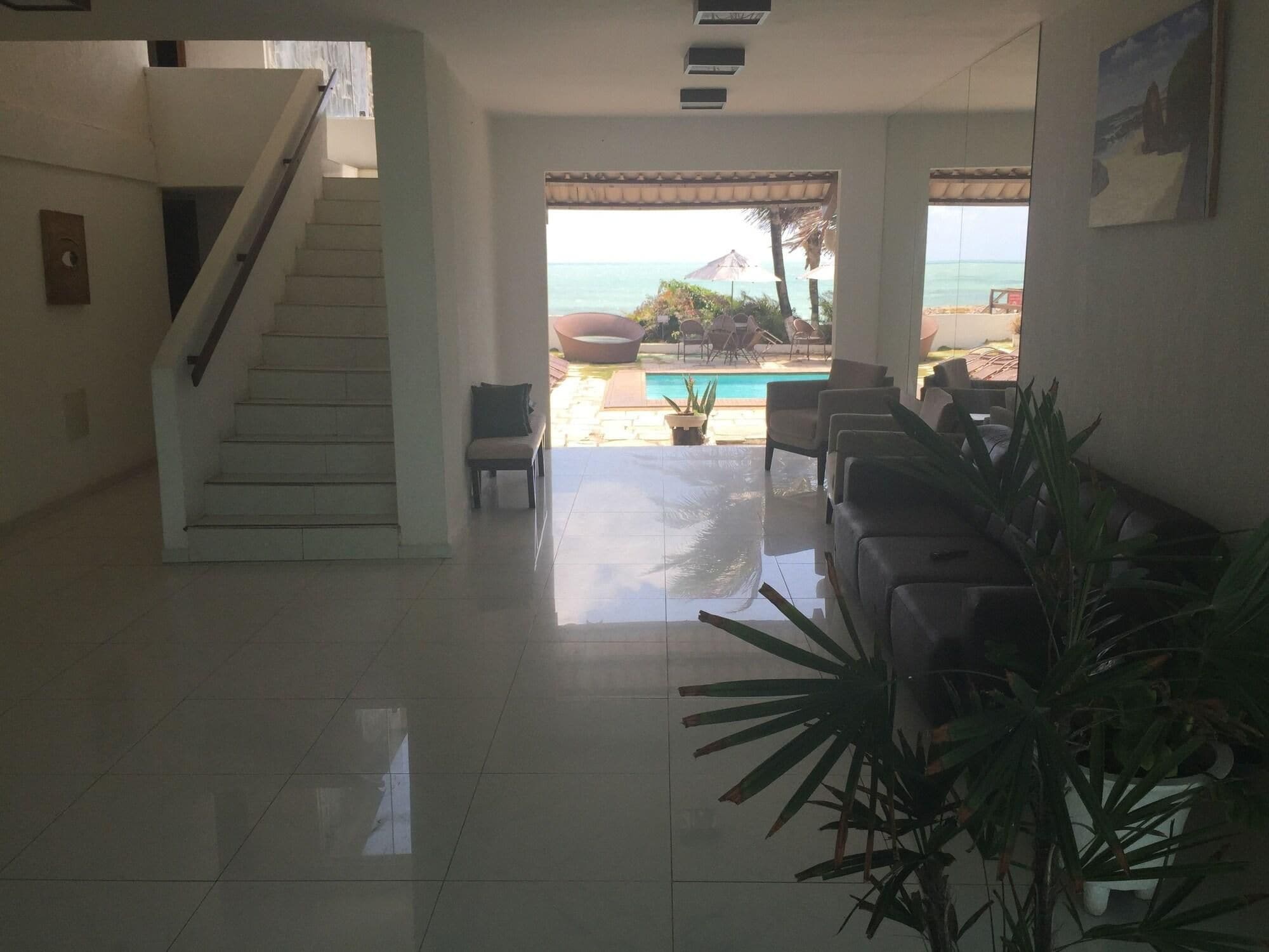 Um saguão de hotel com escadas, área de piscina com espreguiçadeiras e vista para o oceano.