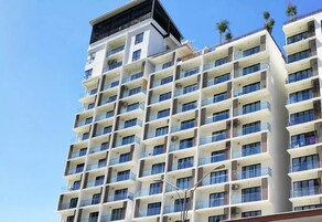 Um hotel de vários andares com varandas, telhado plano e céu claro.