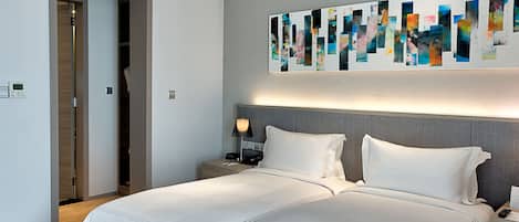 Quarto de hotel moderno com uma cama grande, uma mesa de cabeceira e uma obra de arte na parede.