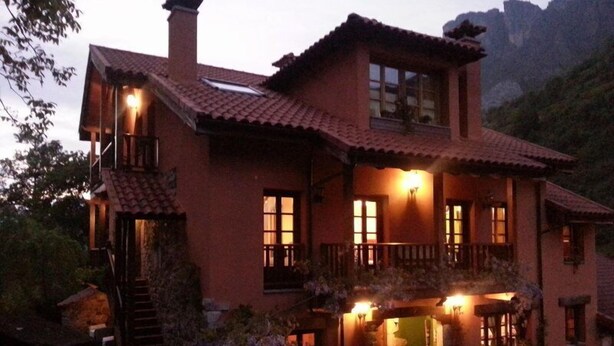 Uma casa de dois andares com varanda, várias janelas e chaminé.