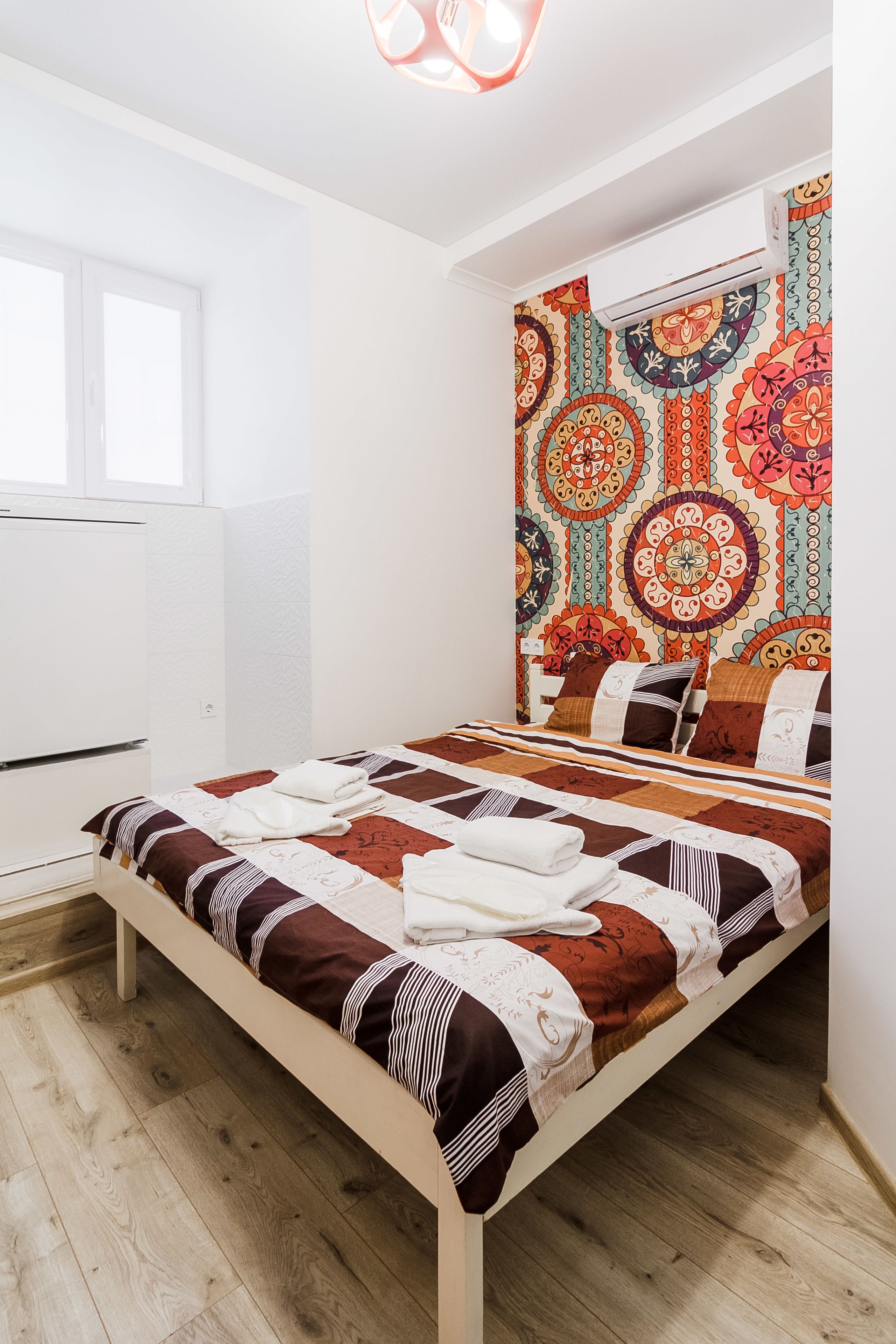 Quarto com cama, guarda-roupa, janela e parede estampada.