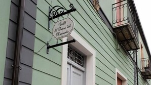 Um edifício com fachada verde, porta branca e um letreiro acima da porta.