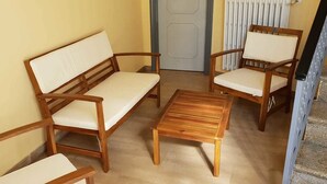 Um quarto pequeno e acolhedor com um sofá de madeira, duas cadeiras de madeira e uma mesa de centro combinando.