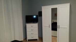 Quarto com cama, televisão em penteadeira e guarda-roupa.