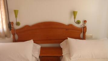 Quarto com cama de madeira, duas mesas de cabeceira, um pequeno banco e arte nas paredes retratando pássaros.