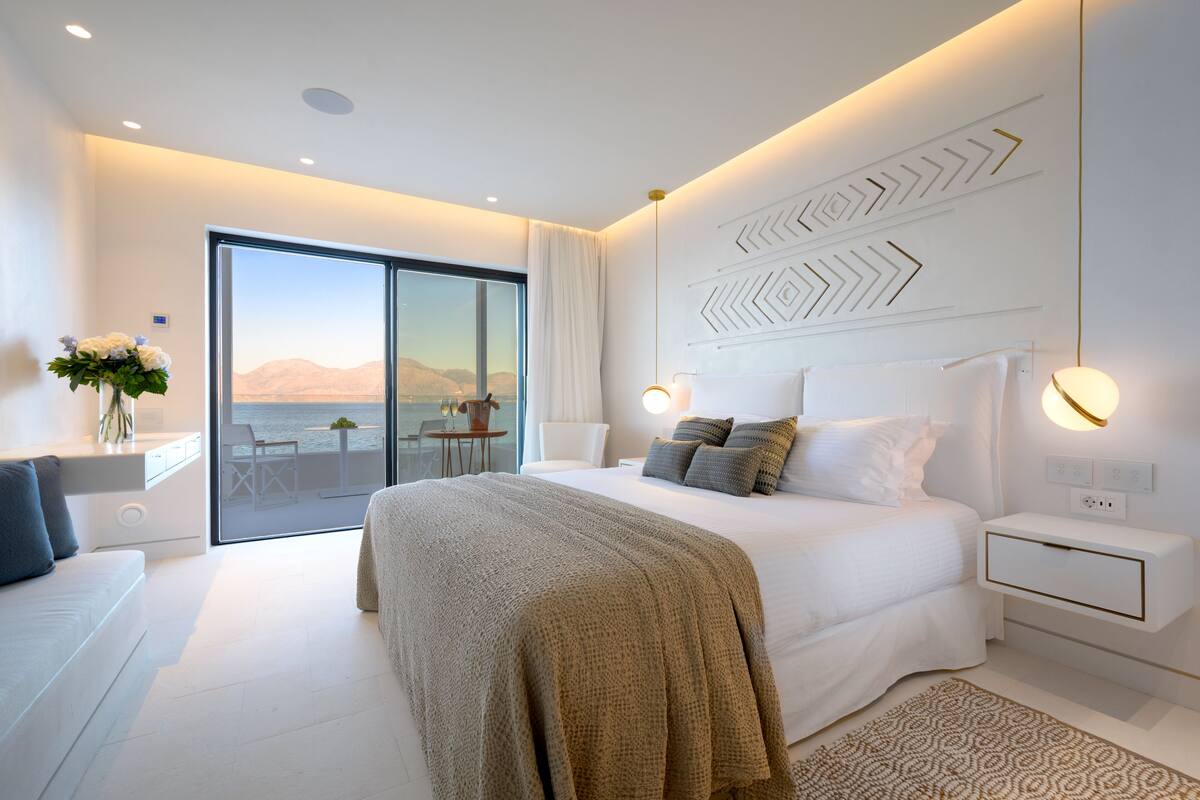 Quarto moderno com uma cama grande, vista para o mar e varanda.