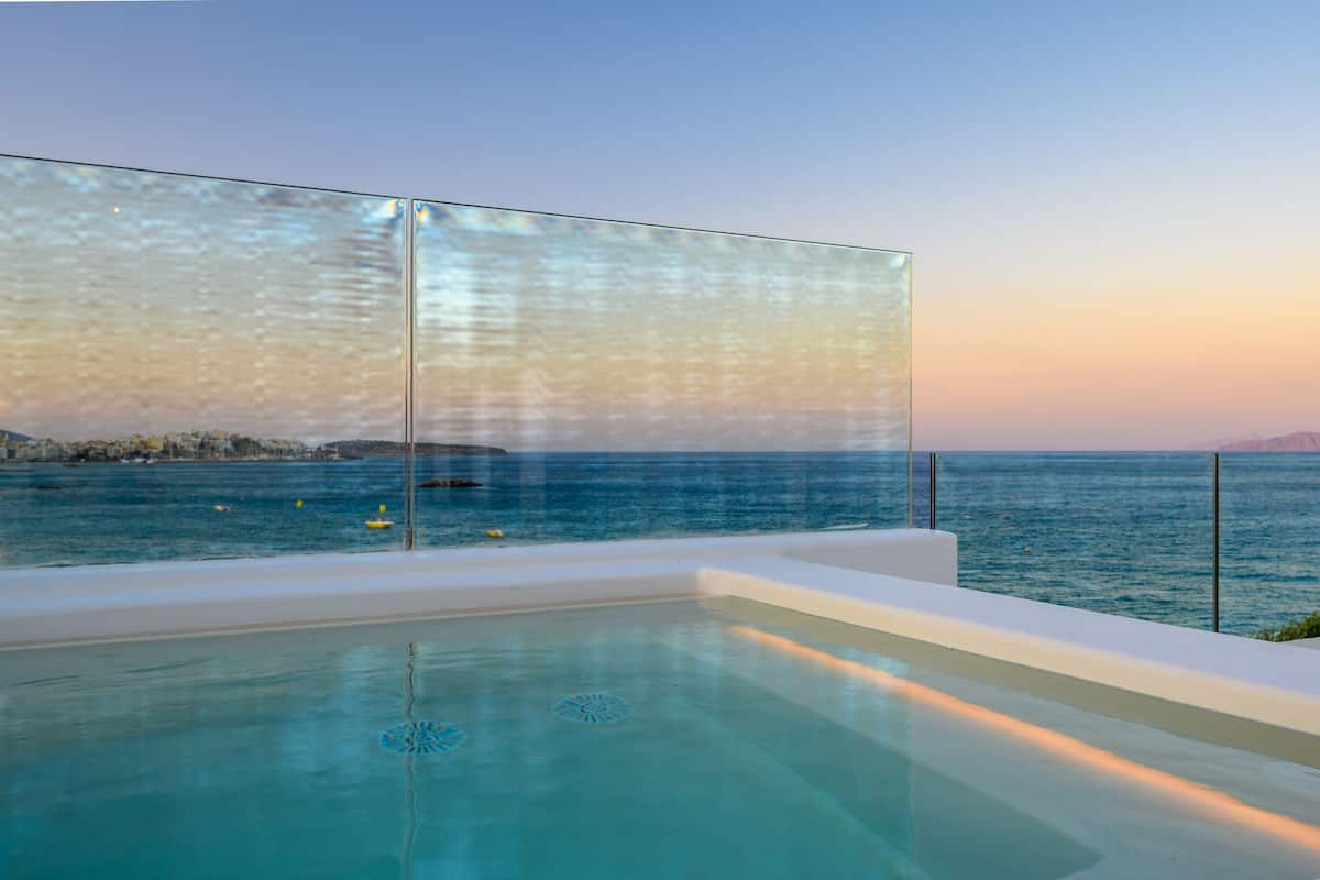 Uma piscina infinita moderna com vista clara para o mar e terra ao longe.