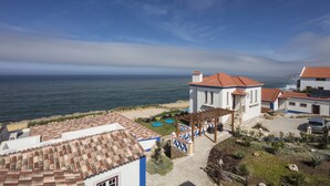 Um imóvel à beira-mar com vista desobstruída para o oceano, piscina e área de varanda coberta.