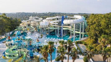 Um parque aquático com várias piscinas e toboáguas, cercado por palmeiras e vegetação.