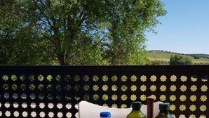 Mesa posta com itens de café da manhã, incluindo torradas, frutas, suco e café, com uma vista panorâmica ao fundo.