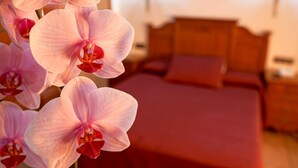 Quarto com cabeceira de madeira, colcha vermelha e mesa de cabeceira com abajur.