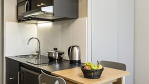 Cozinha moderna com uma pia de aço inoxidável, chaleira e uma cesta de frutas no balcão.