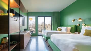Quarto de hotel moderno com duas camas, uma escrivaninha e uma varanda com vista.