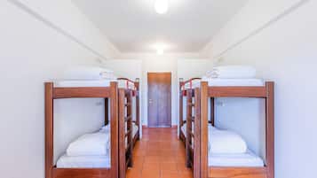 Corredor com beliches, uma porta e luminária.