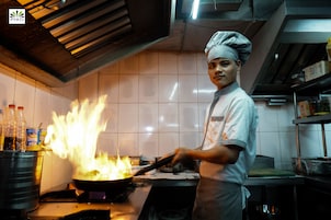 Um cozinheiro preparando comida numa panela em uma cozinha.