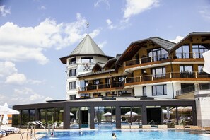 Um hotel com piscina, várias varandas e uma torre imponente.