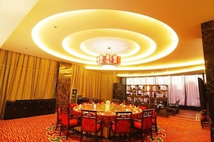 Um salão de refeições de hotel com uma mesa redonda, cadeiras vermelhas e um candelabro.