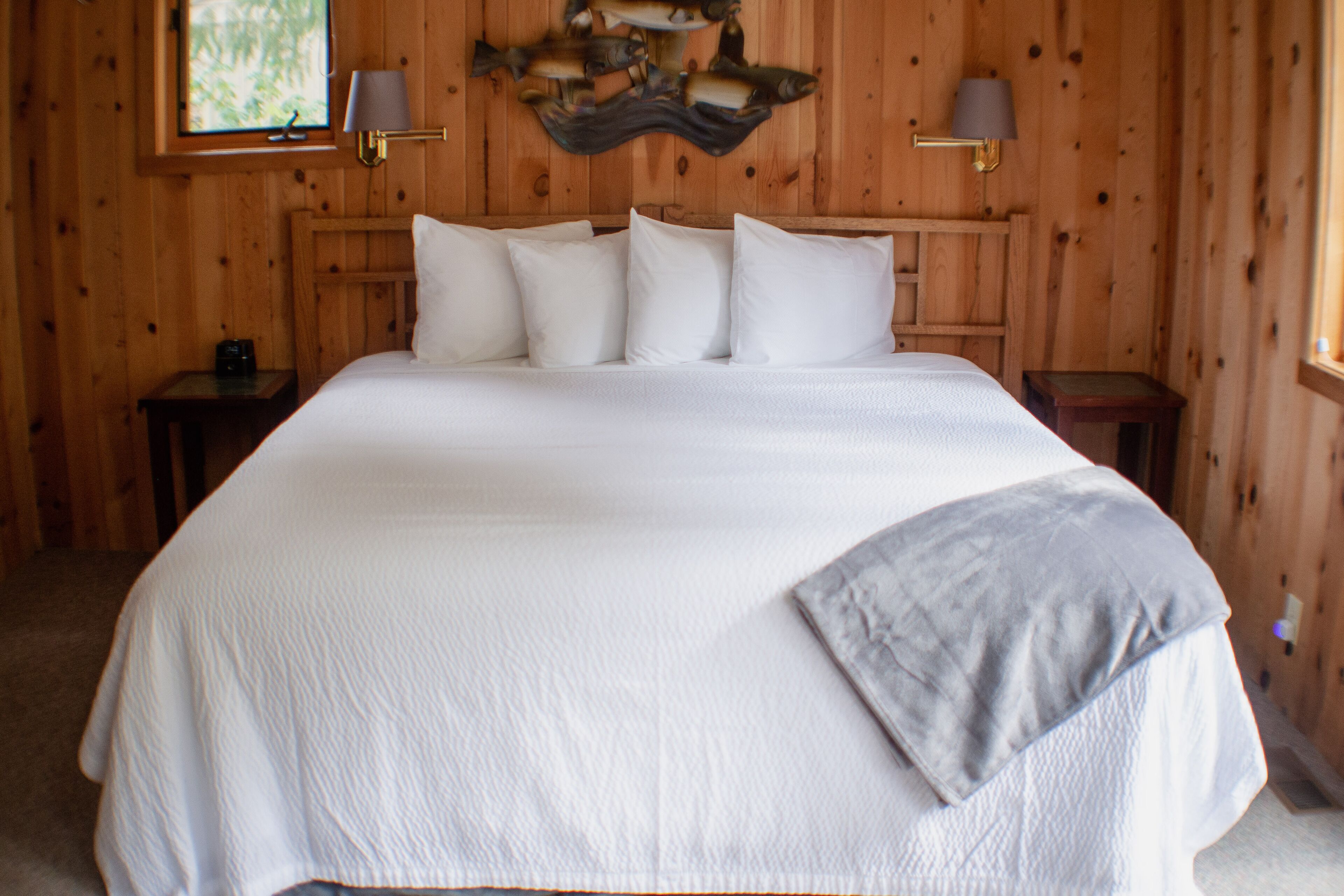 Uma cama grande com roupa de cama branca num quarto de madeira.