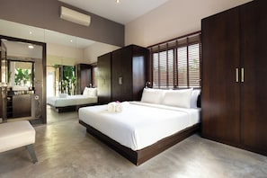 Quarto de hotel moderno com uma cama grande, um espaço de estar e um espelho.