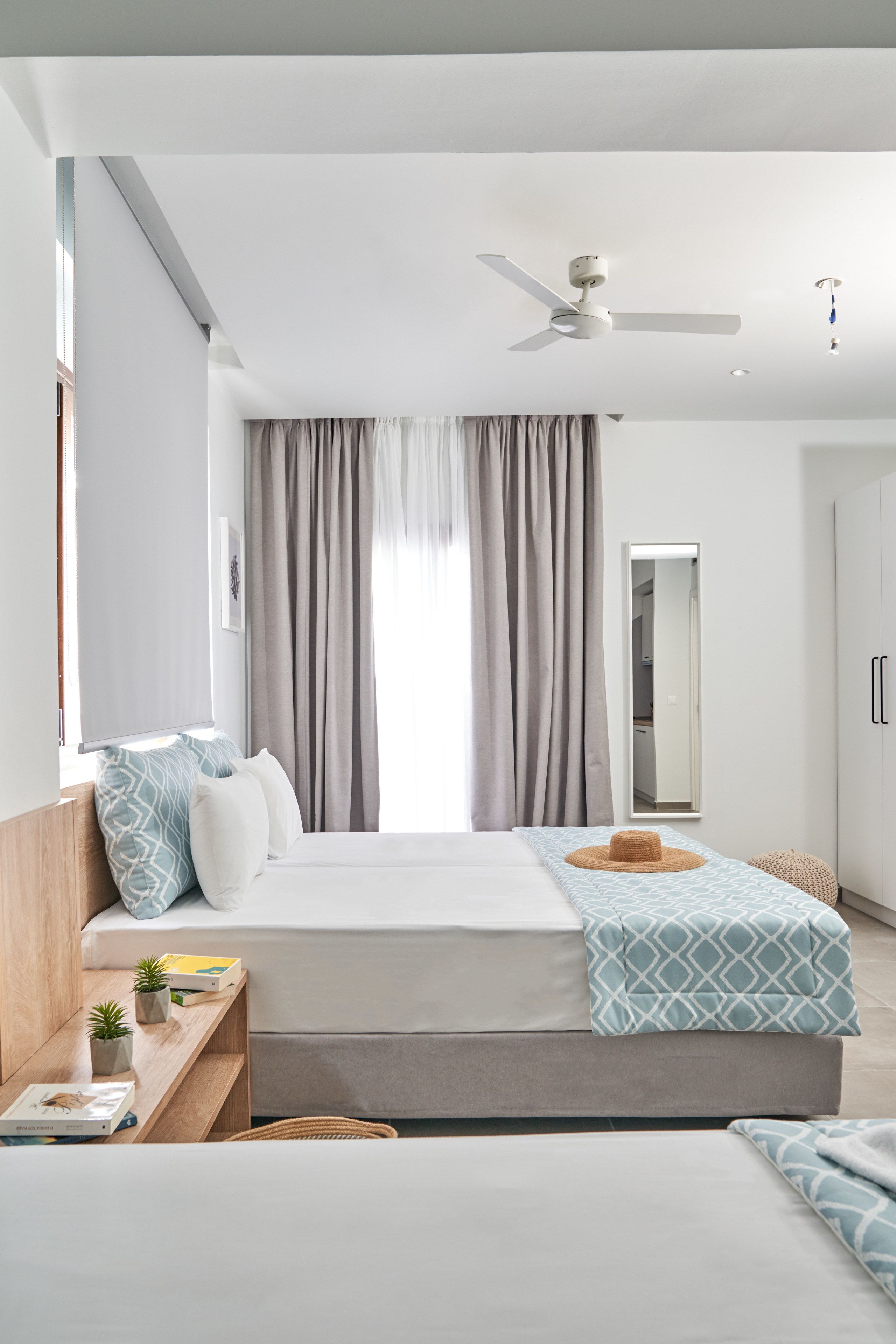 Quarto moderno com cama, mesa de cabeceira e ventilador de teto.