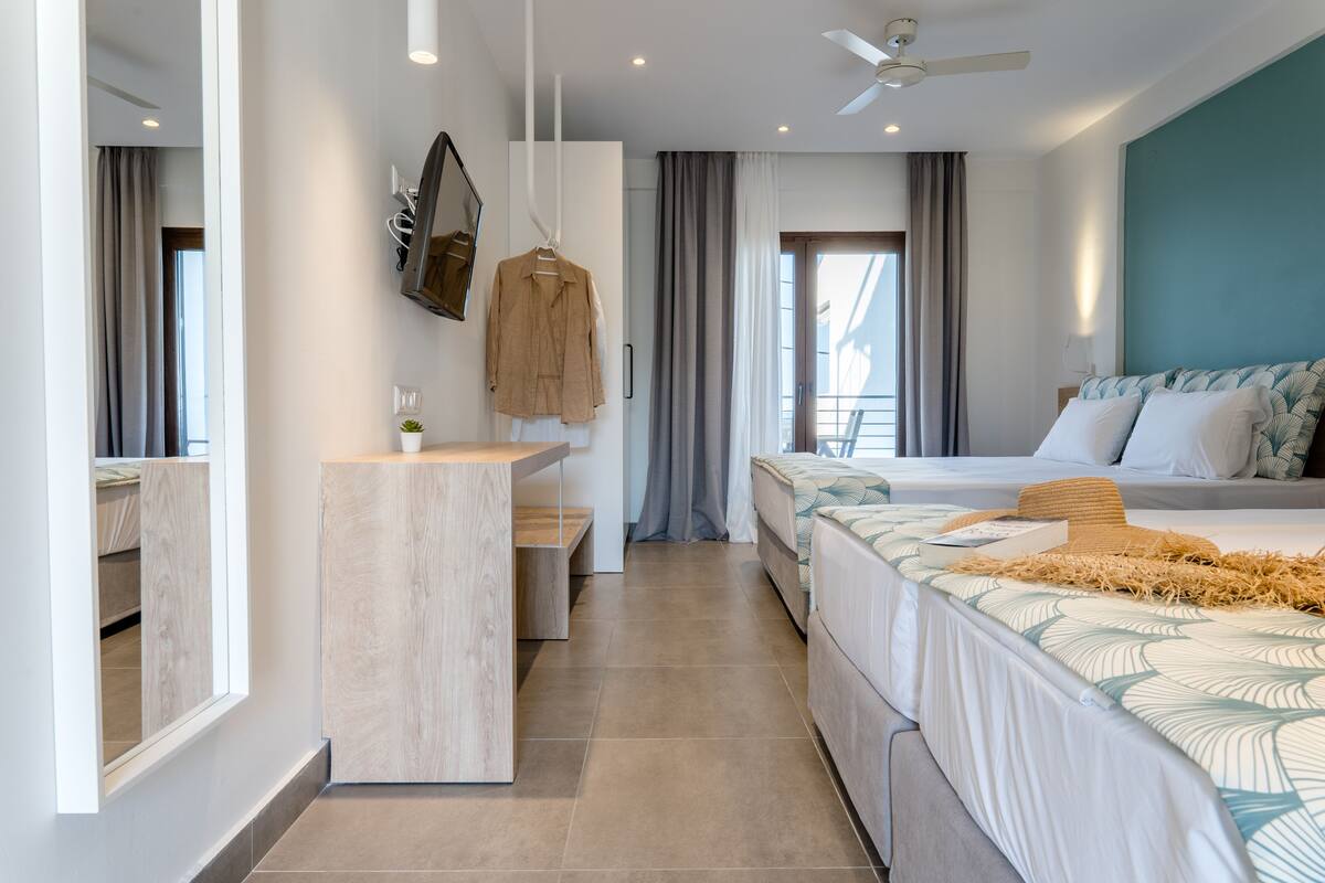 Quarto de hotel moderno com uma cama, uma mesa de escritório e uma janela grande.