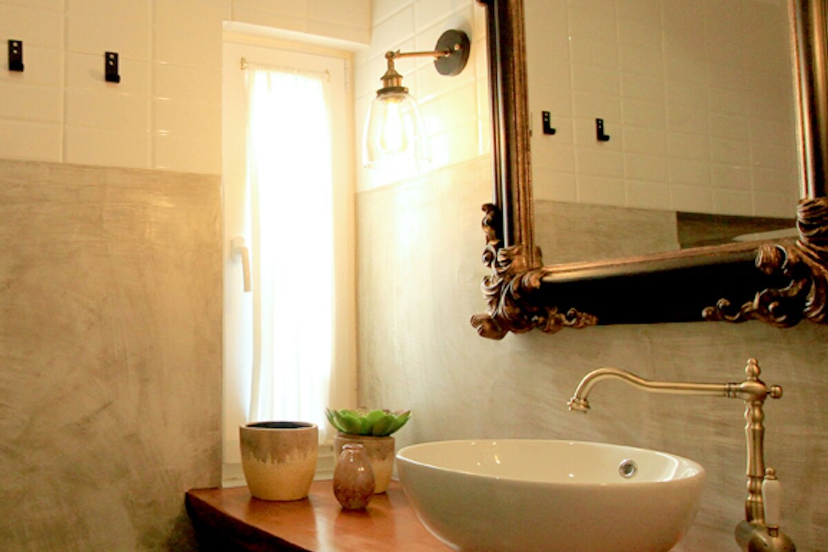 Um banheiro com parede de mármore, pia com torneira dourada e espelho com moldura ornamentada.