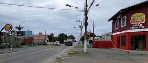 Vista da rua com um prédio vermelho identificado como 'Pousada Vista do Parque' e uma placa indicando 'Porto Peninsular Eisenbahn'.